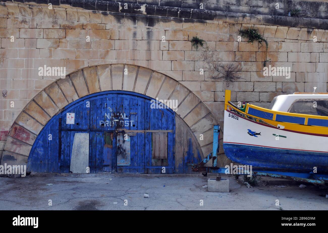 A traditional fishing boat sits on a trailer near an old naval provost ...