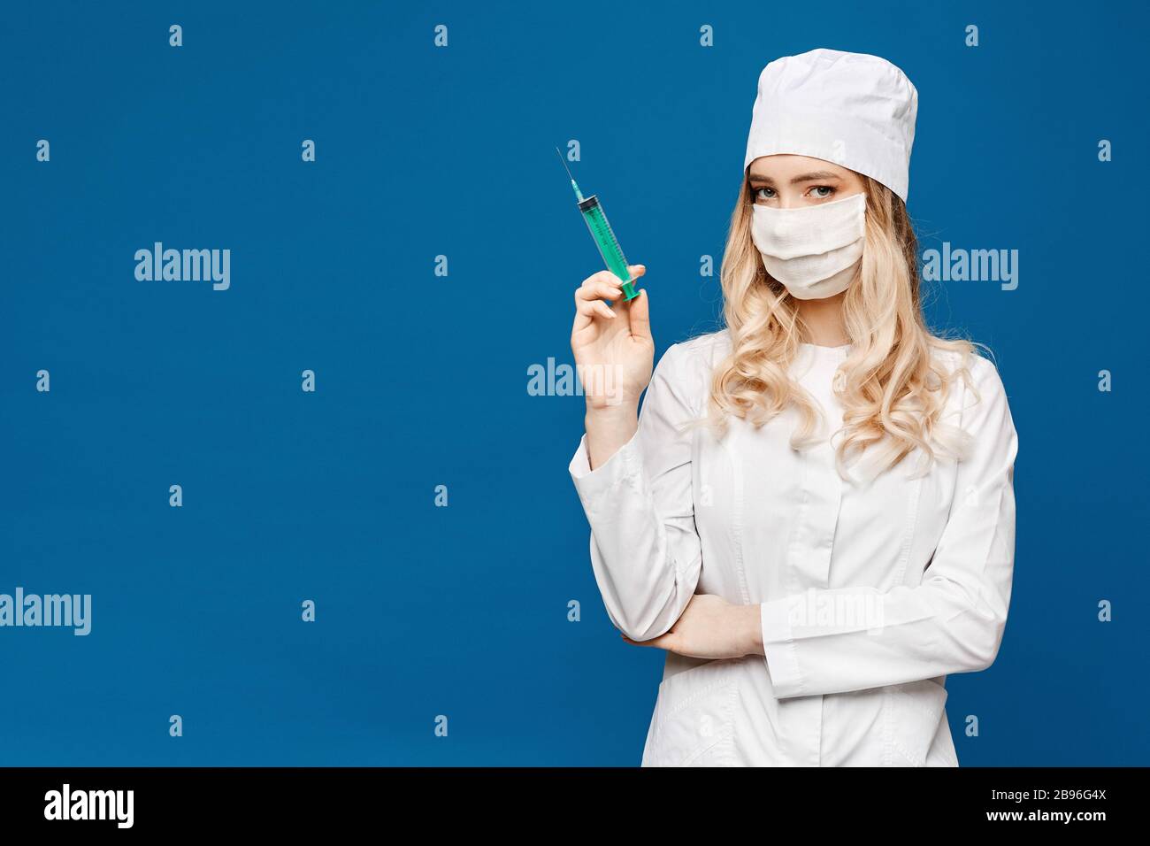 Beautiful young nurse in medical robe holding syringe, isolated over ...