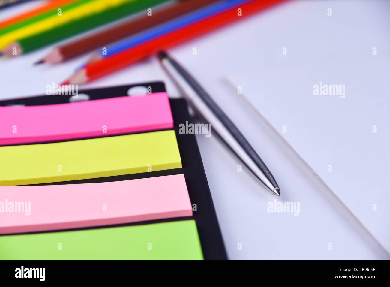 Metal pen and multi-colored blank stickers close-up on the office desk ...