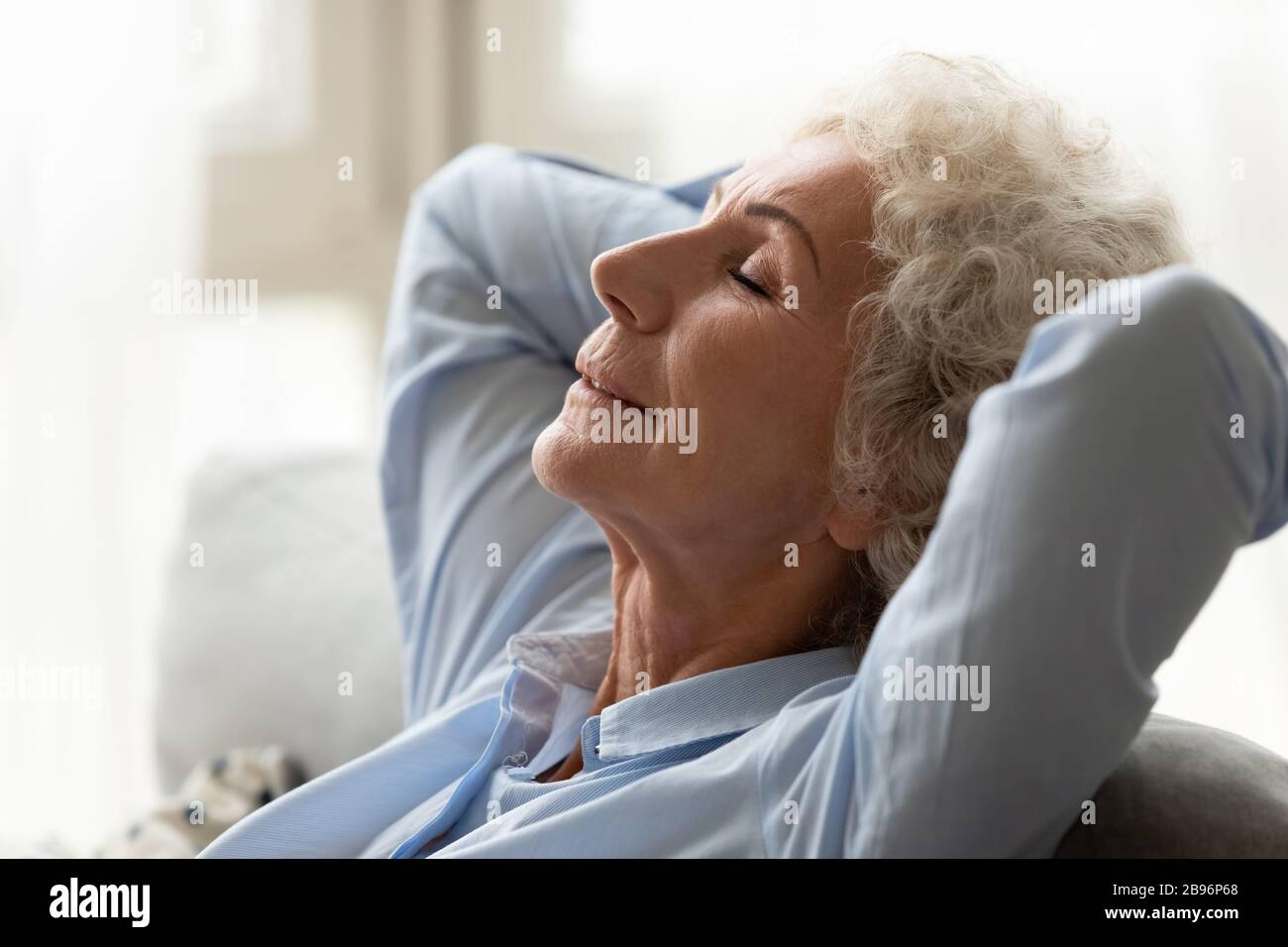 Calm old woman relax on couch in living room Stock Photo - Alamy