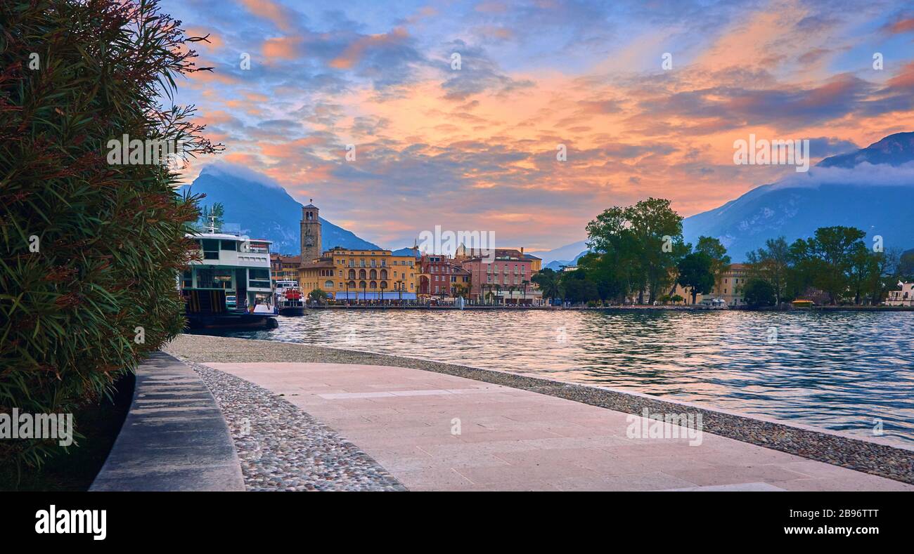 View of the beautiful Riva del Garda town at sunset with a red sky ...