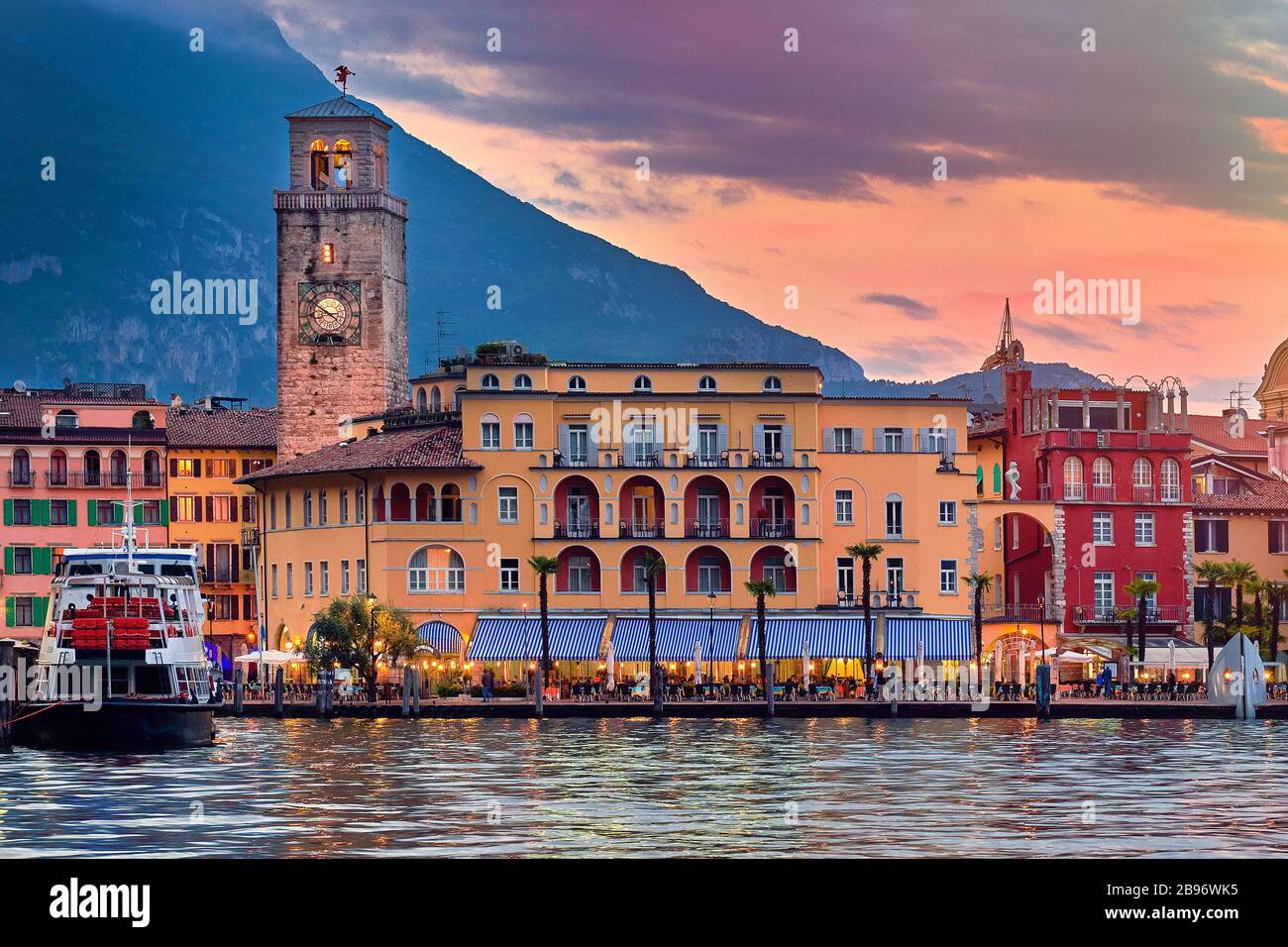 View of the beautiful Riva del Garda town at sunset with a red sky ...