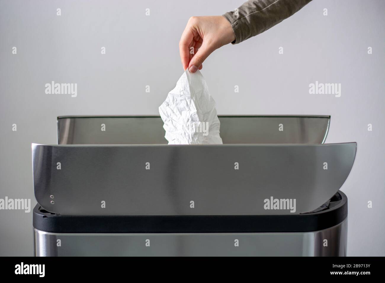 Women hand throwing a white used crumpled tissue paper into a trash bin ...