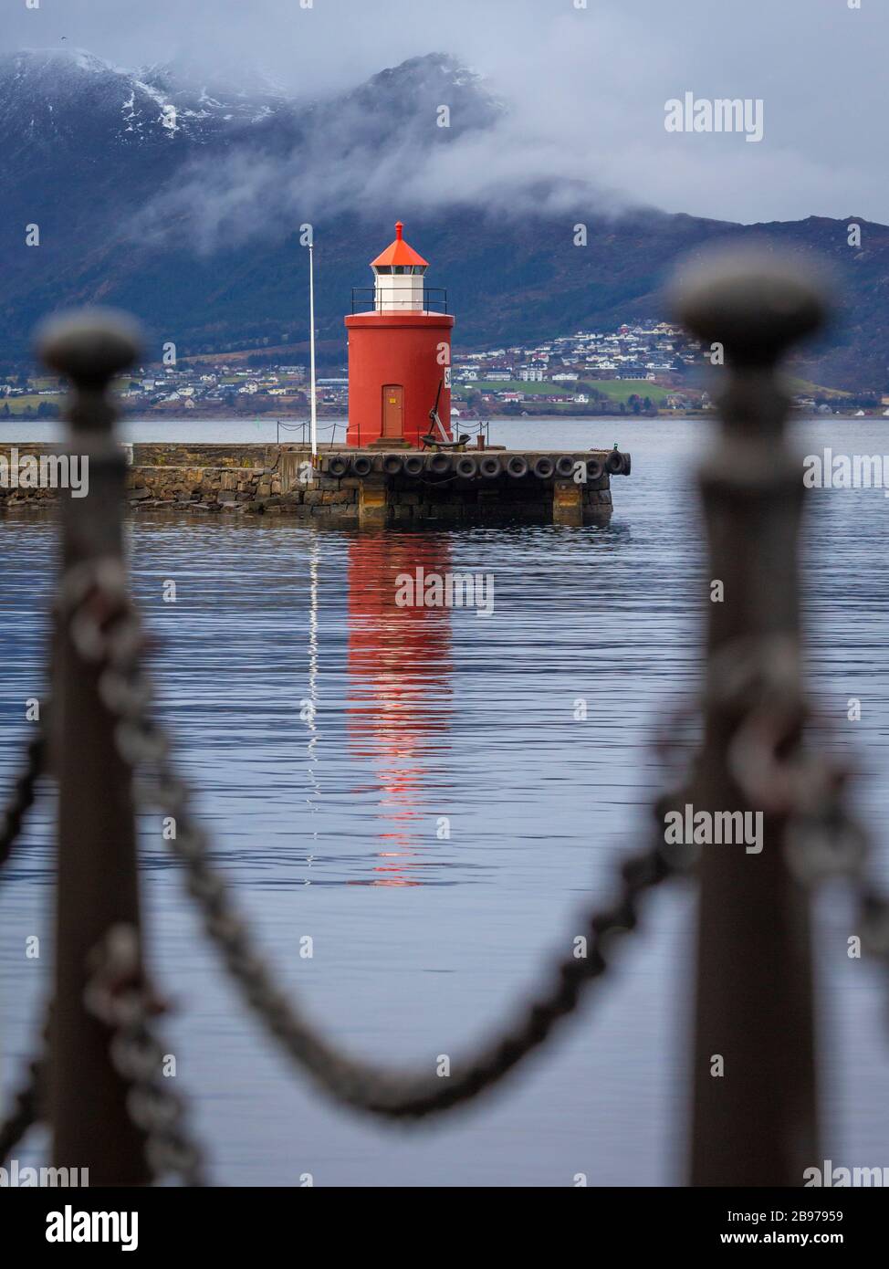 Red lighthouse and an old anchor at the port entrance of Alesund at the ...