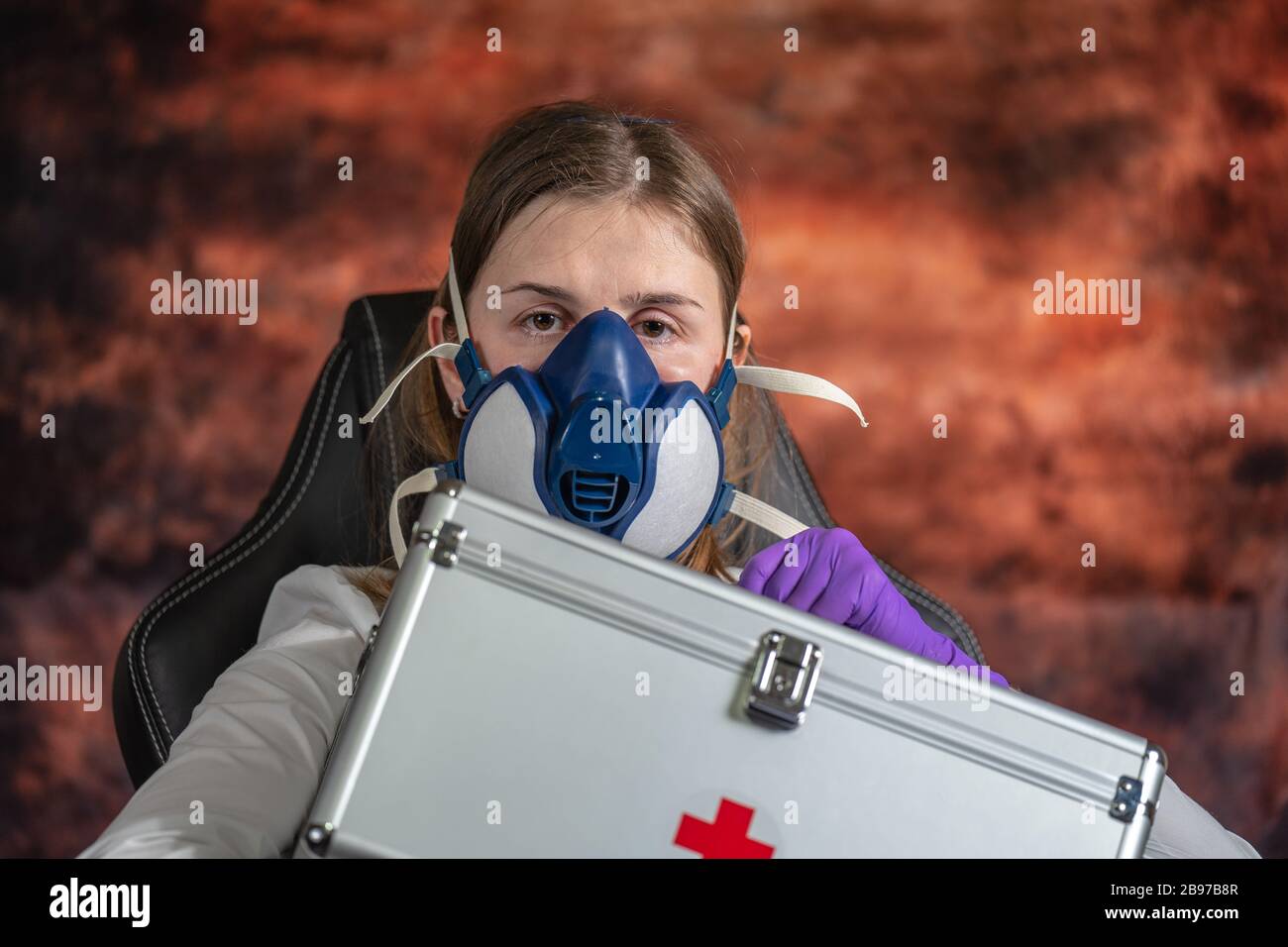 Woman in a gas mask sitting in chair with first aid kit. Coronovirus ...