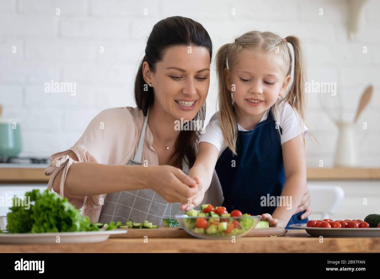 Young mom and little daughter cook together Stock Photo - Alamy