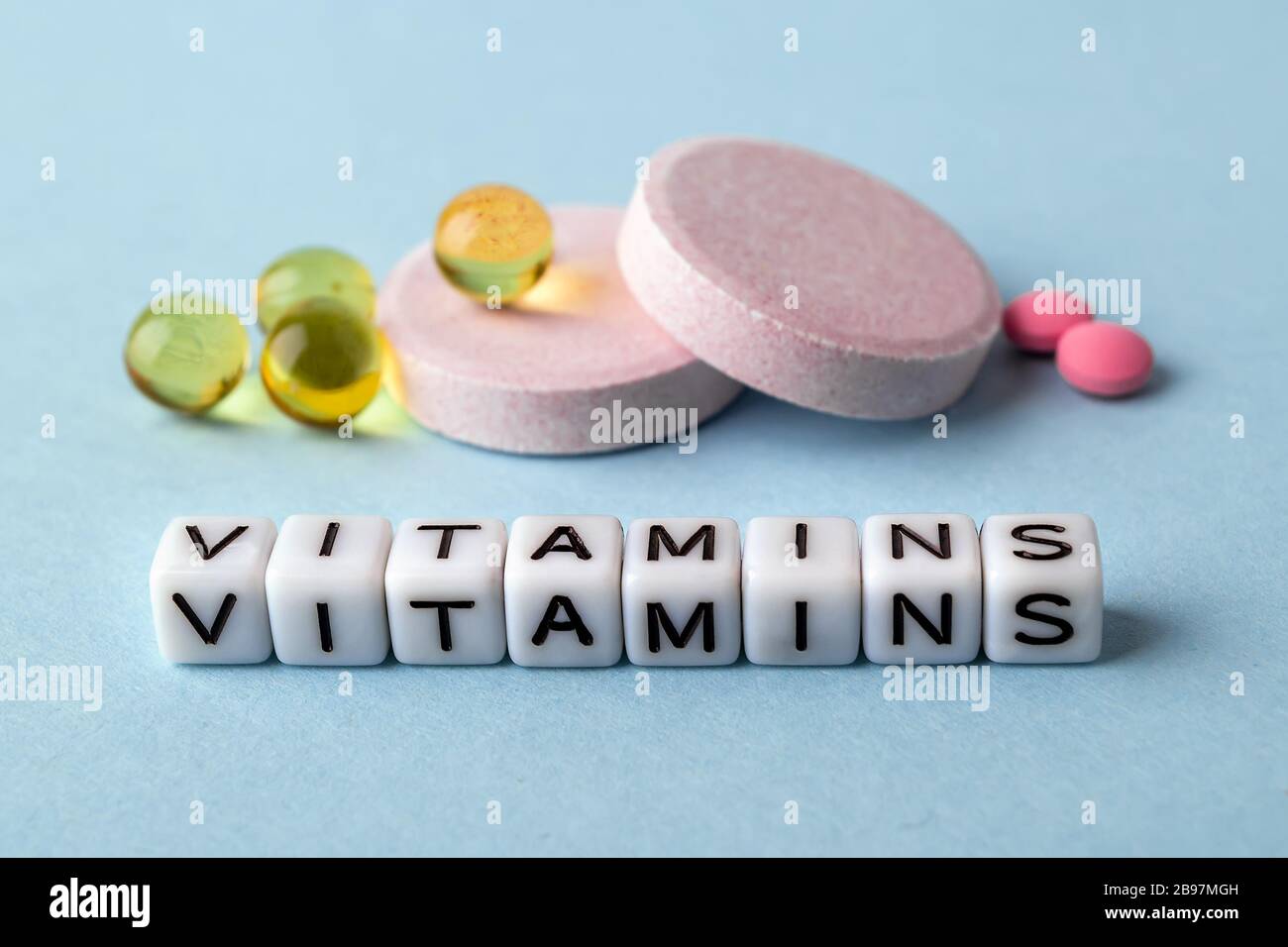 Word Vitamins made of white cubes and different vitamins on a blue ...
