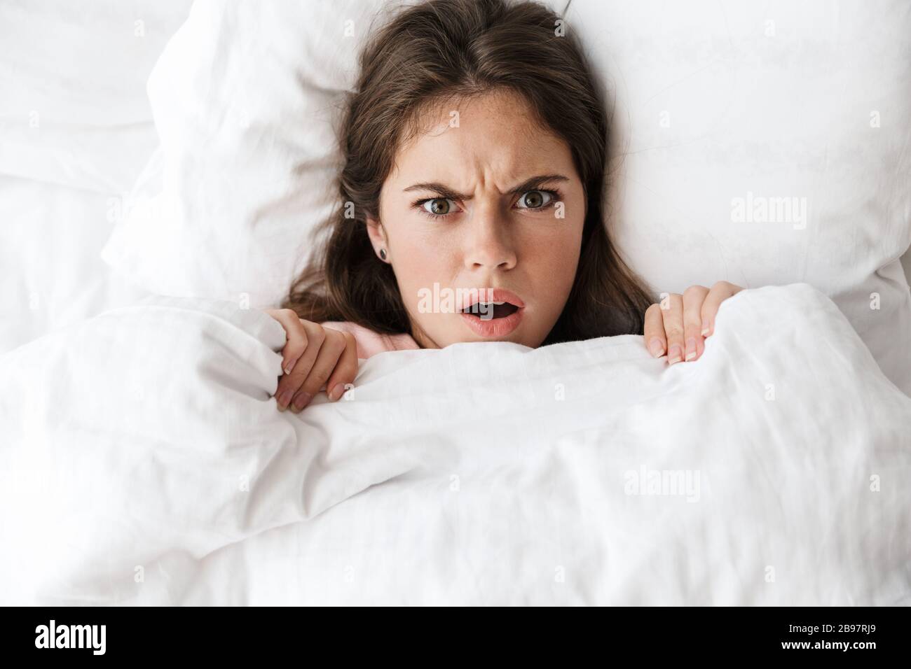 Top View Of An Angry Young Girl Resting In Bed At The Bedroom Covers