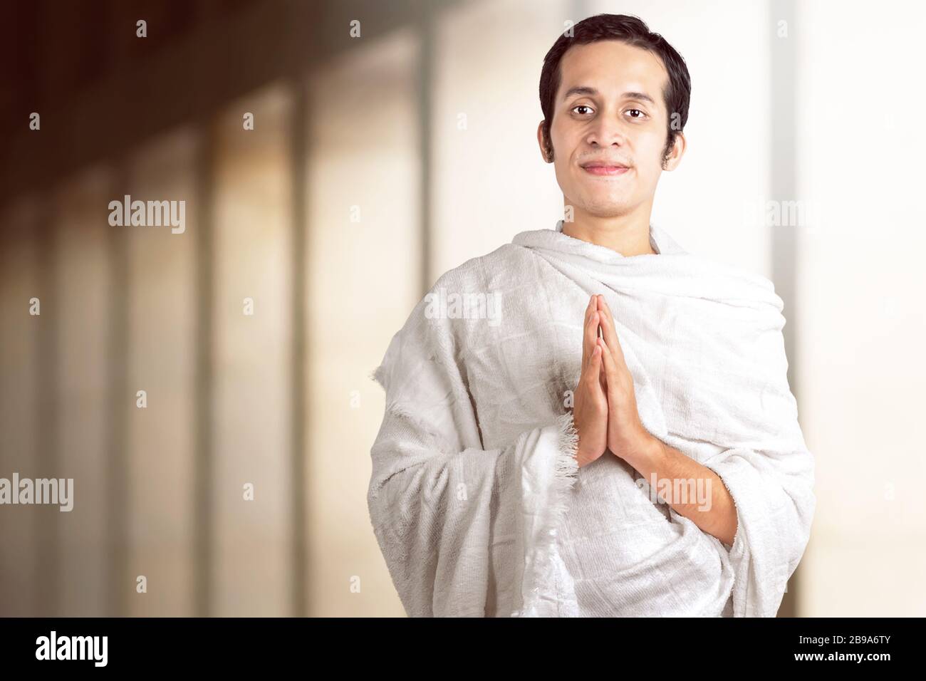 Asian Muslim man in ihram clothes standing and praying inside the ...