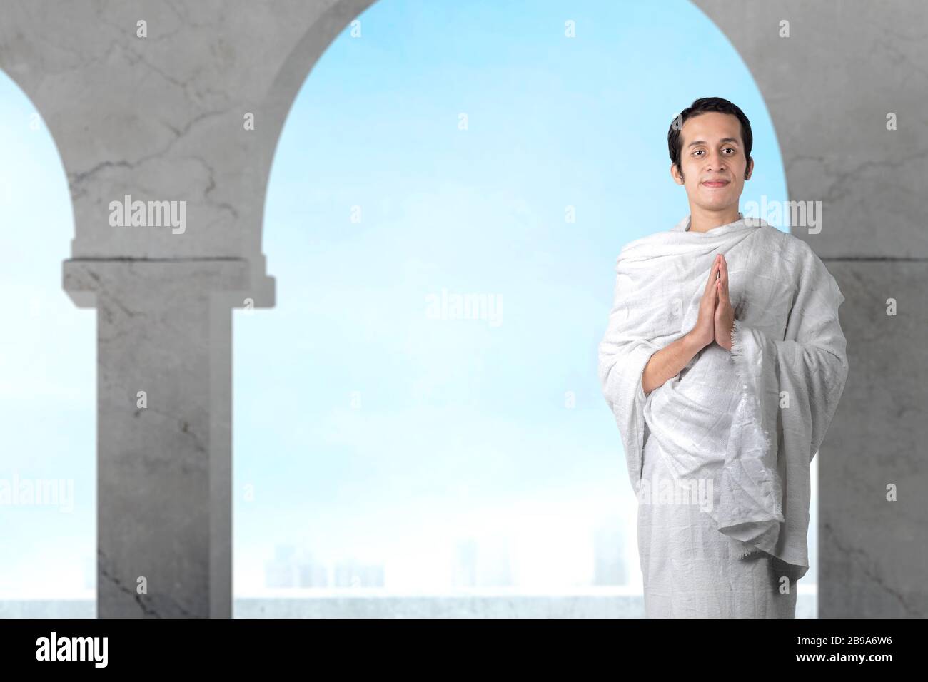 Asian Muslim man in ihram clothes standing and praying inside the ...