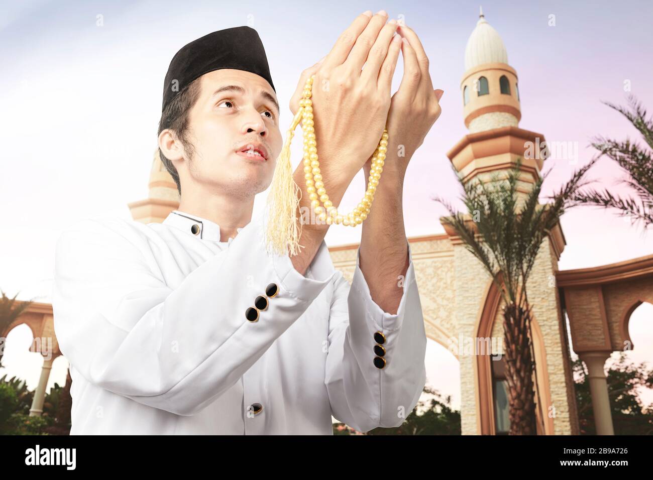 Asian Muslim man praying with prayer beads on his hands outside the ...