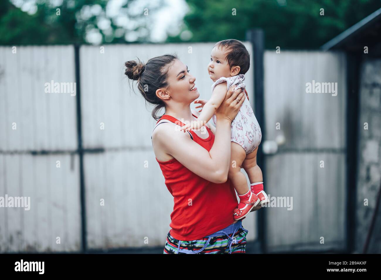 Beautiful Mother And Baby outdoors on the yard of house. Beauty Mum and ...
