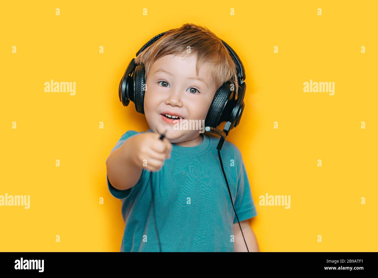 A smiling boy unplug his headphone and show plug to camera on isolated ...