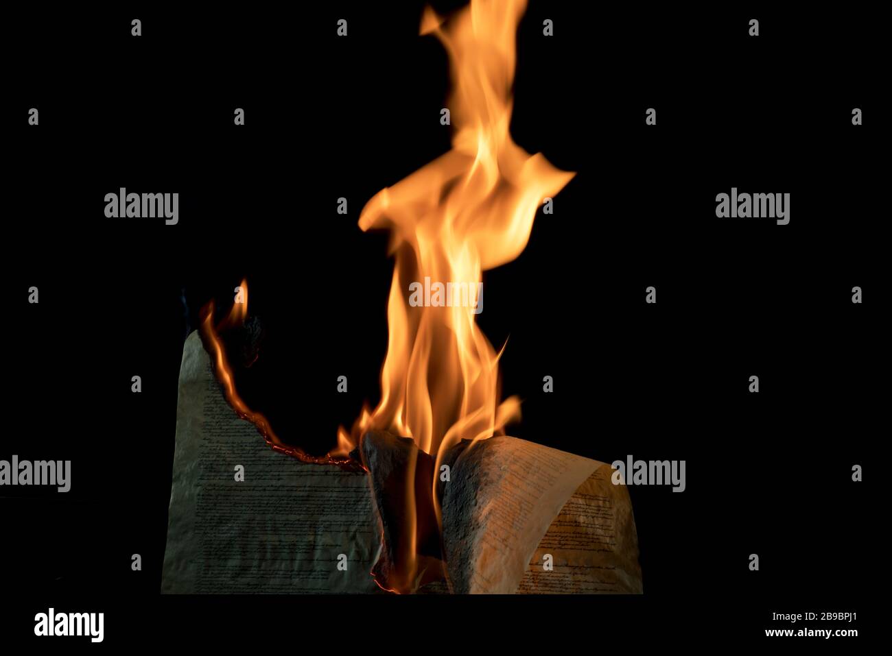 Paper document being burned with rising flames against a black ...