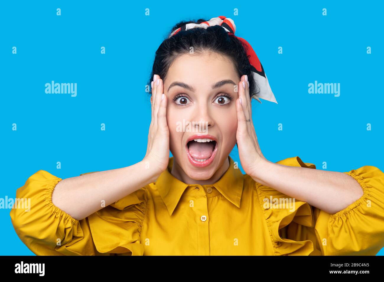 Young woman in a mustard dress holding head Stock Photo - Alamy