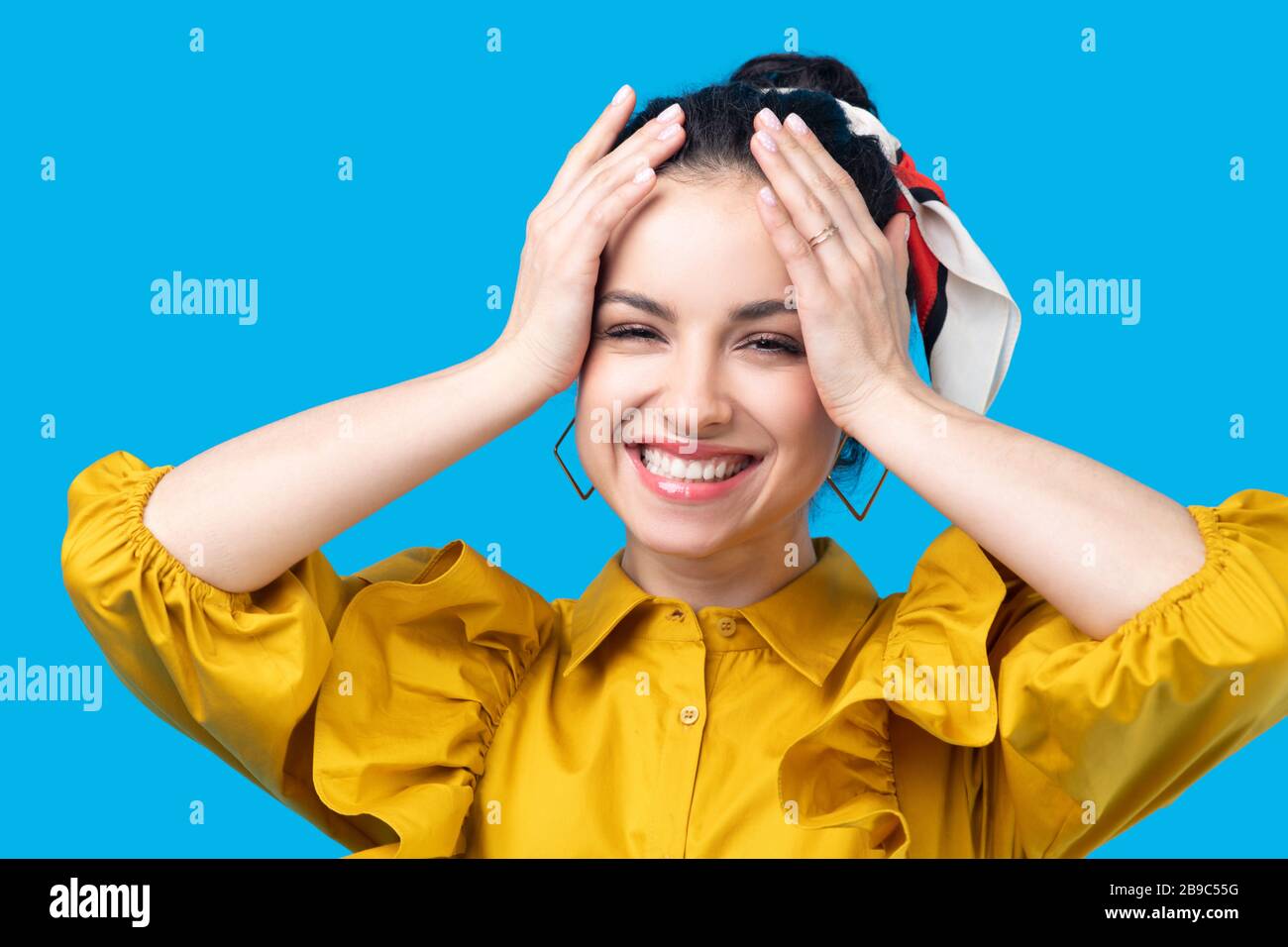 Young woman in a mustard dress holding her head and smiling Stock Photo ...
