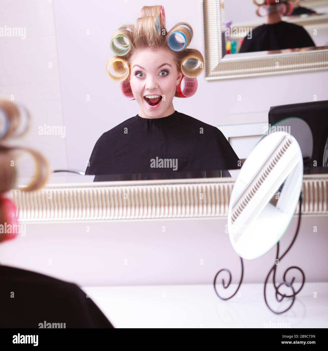 Portrait of funny happy woman in beauty salon. Cheerful blond girl with ...