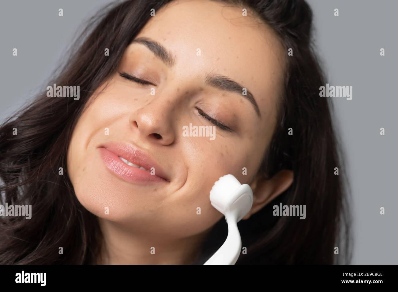 Beautiful dark-haired girl brushing her face with a face brush Stock ...