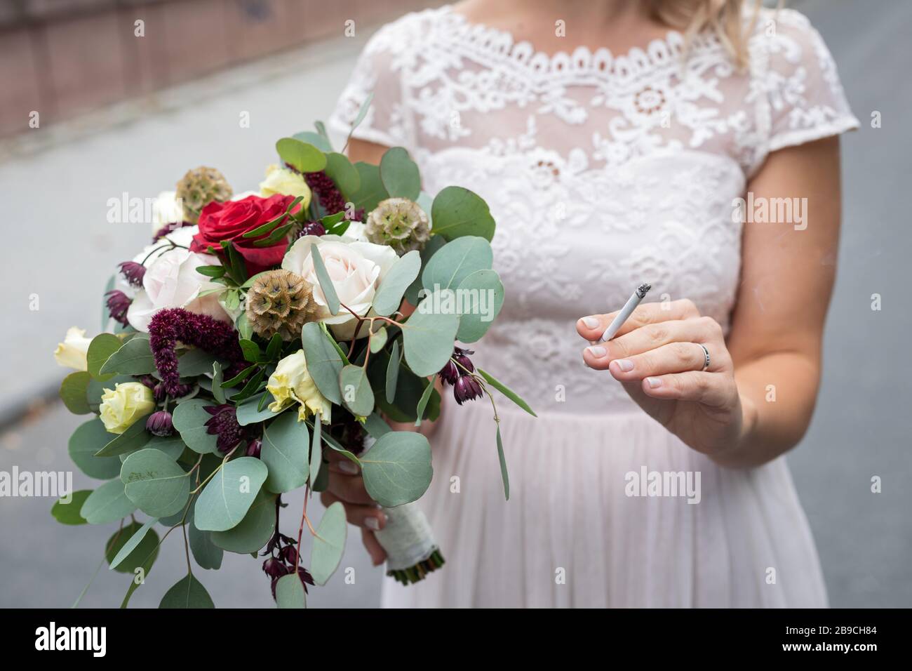 Bride holding wedding bouquet and cigarette , smoking on wedding day ...