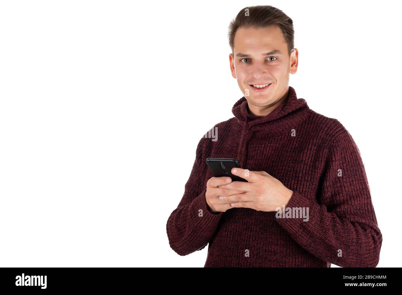 Young man holding a smartphone looking to the camera on isolated ...