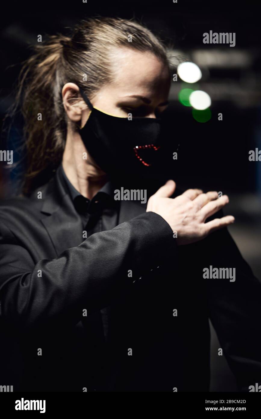 A young girl in a black virus protective mask in a black jacket suit on ...