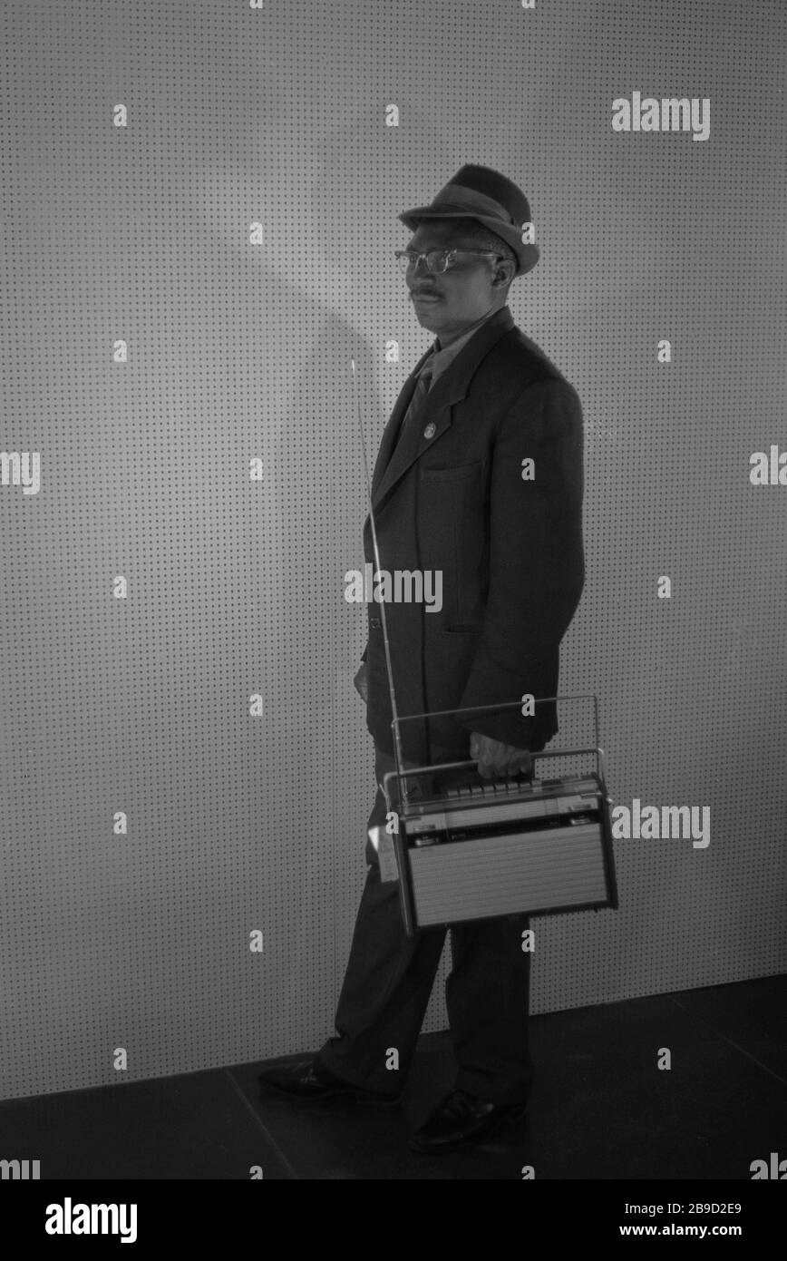 A man with a hat and a portable radio in his hand. [automated ...