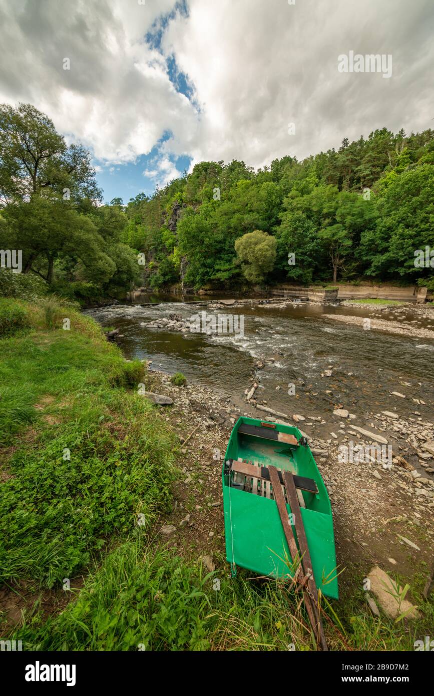 small green boat on the side of river with low water level in forests ...