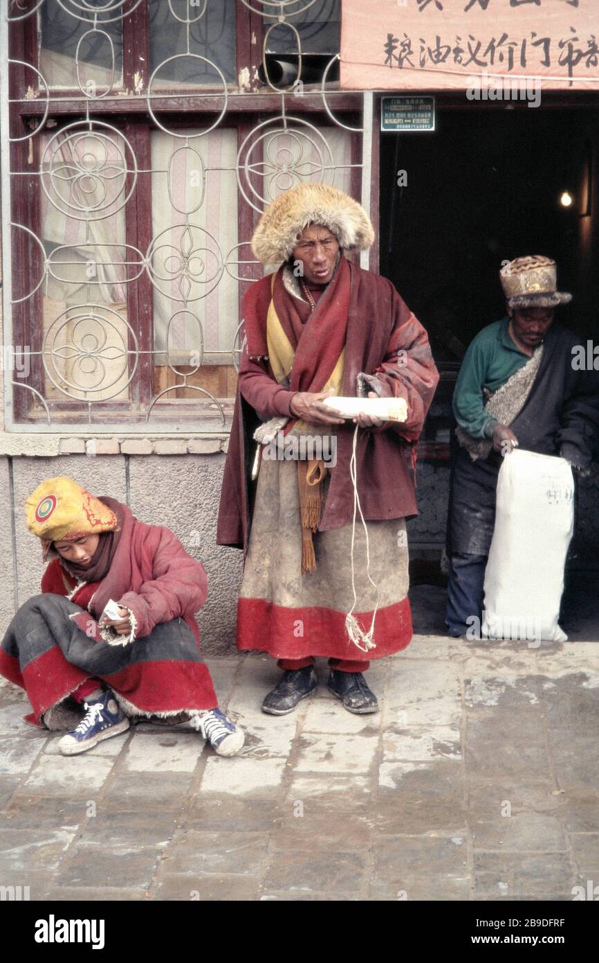 Two Uighurs in red robes in front of a shop in Xining. [automated ...