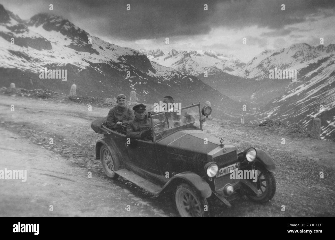 Three men are sitting in a car on a pass road in the Alps. [automated ...