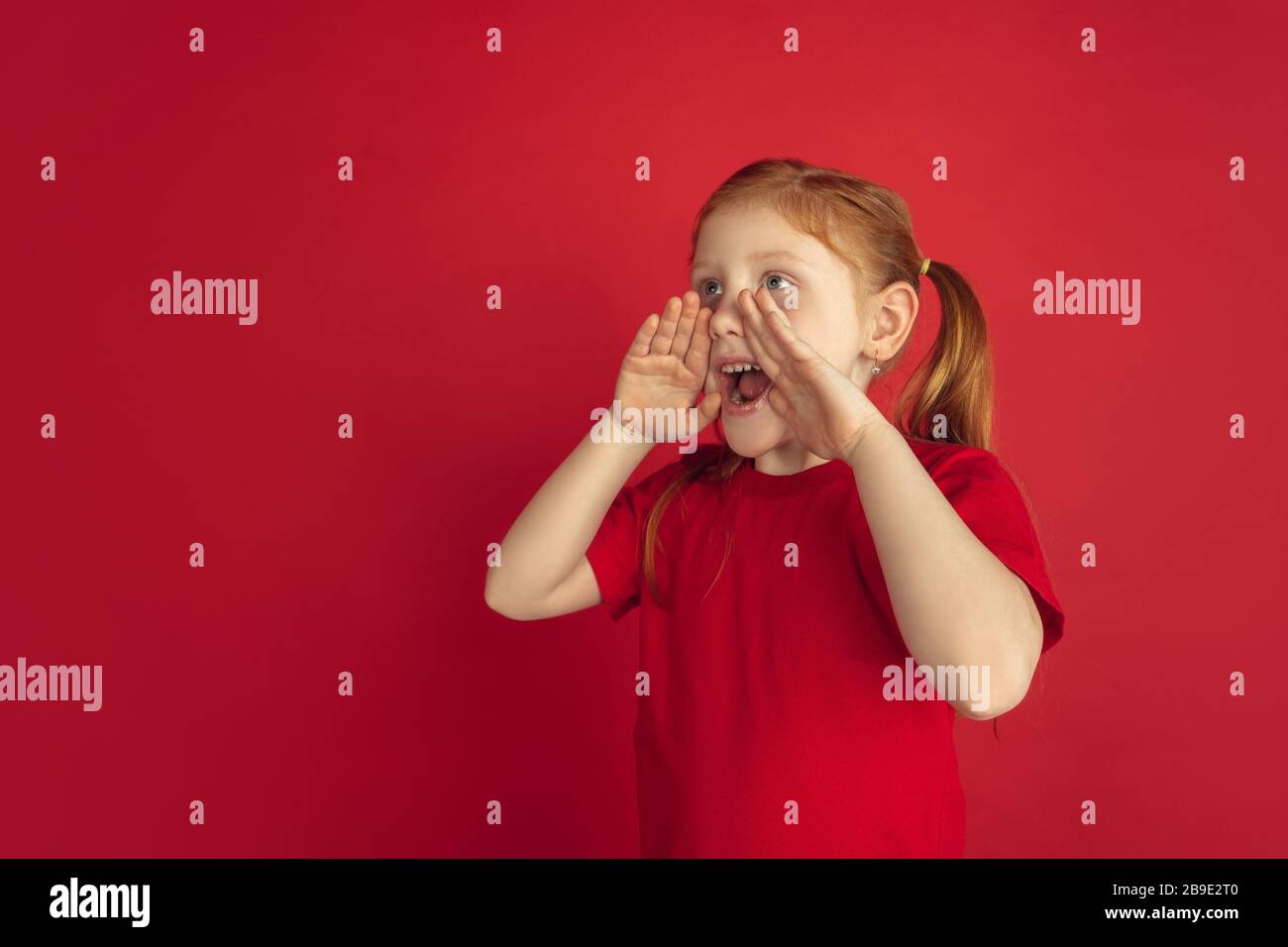 Calling, shouting. Caucasian little girl portrait isolated on red ...