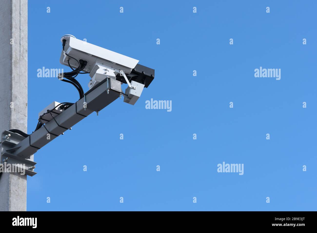 Closeup of speed camera surveillance on the road. Concrete pillar, blue ...