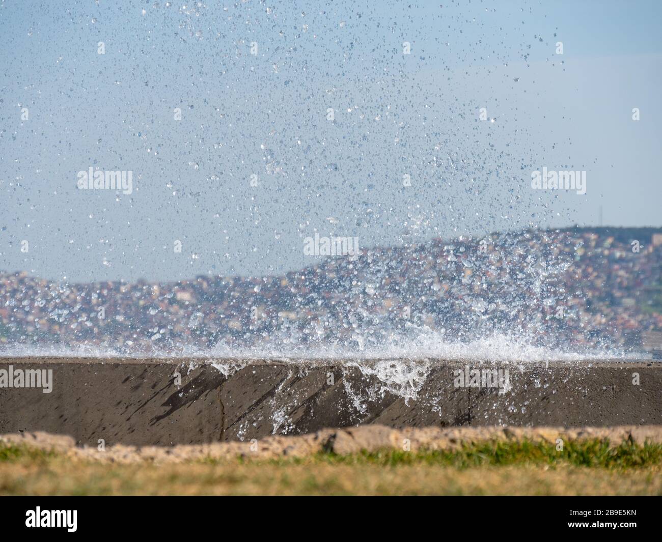 Waves hit the hard surface of concrete wall and splashing sea water ...