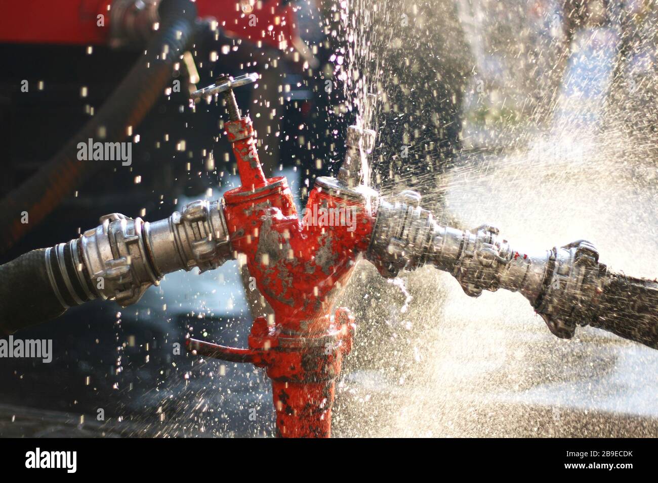 Water splashes from the fire hose and hydrant connections. Firefighters ...
