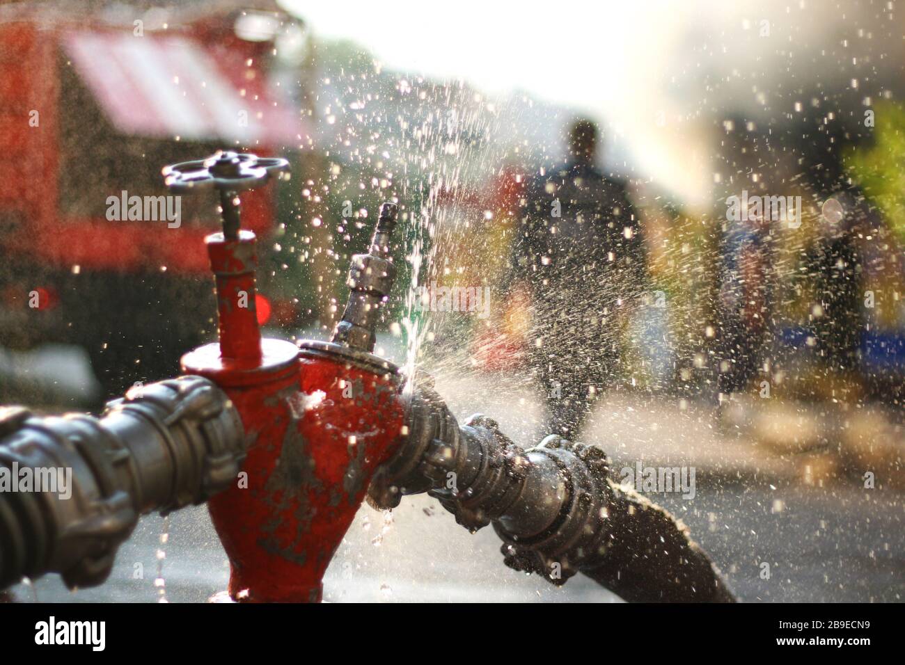 Water splashes from the fire hose and hydrant connections. Firefighters ...