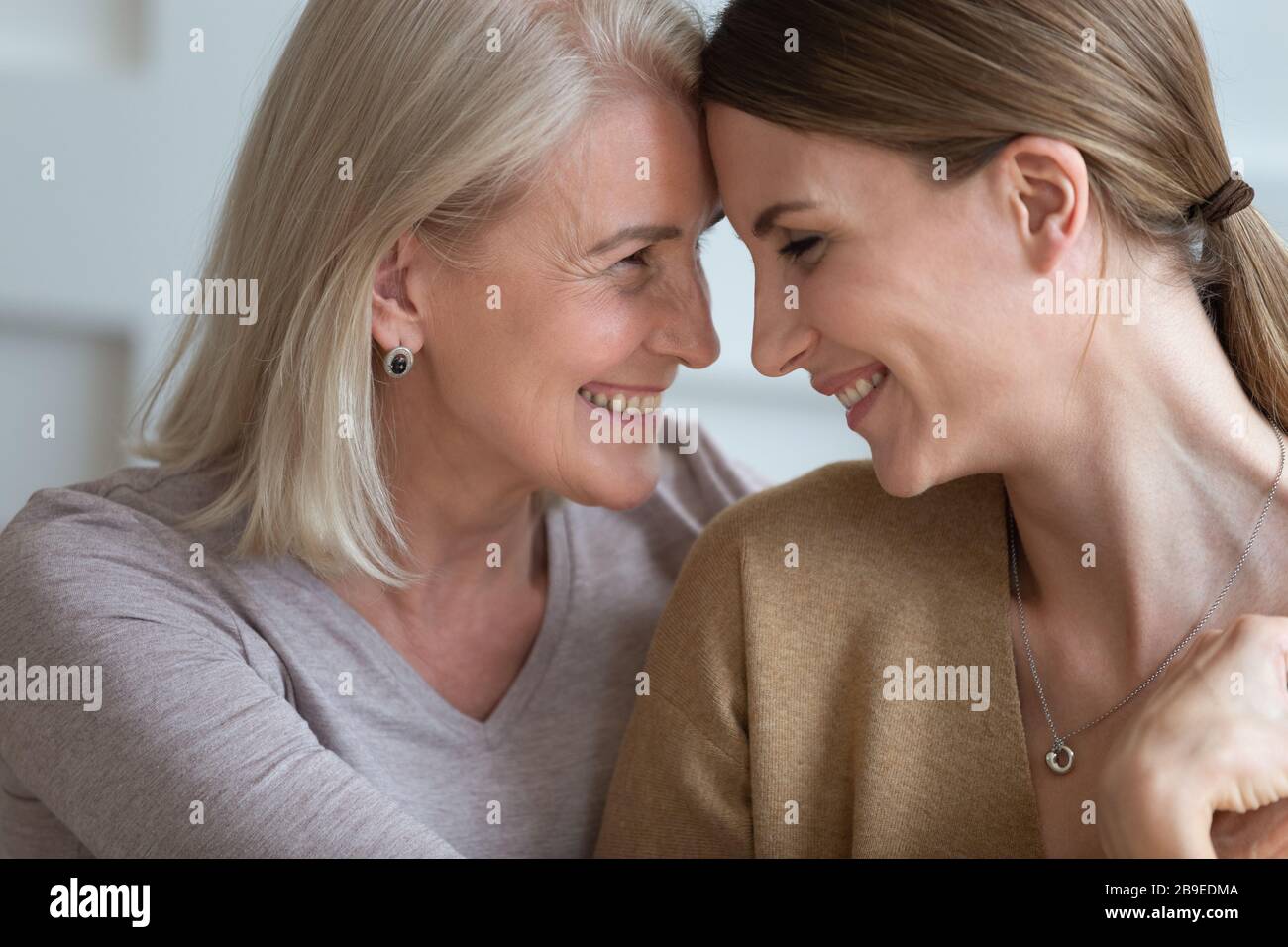 Happy older mother and adult daughter touching foreheads, feeling love ...
