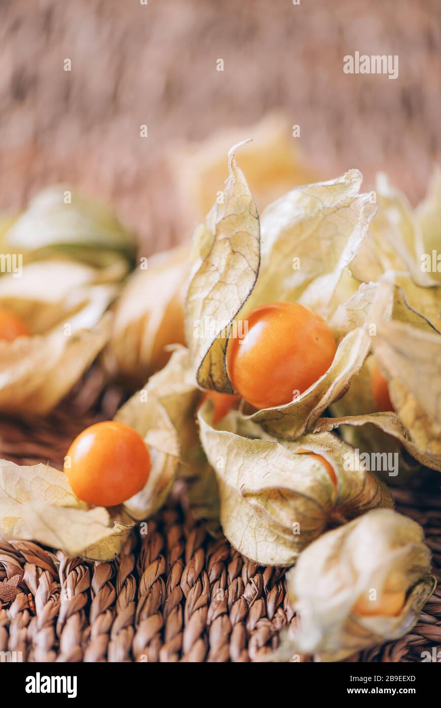 Physalis fruit with husk over palm leaves on rattan background. Copy ...