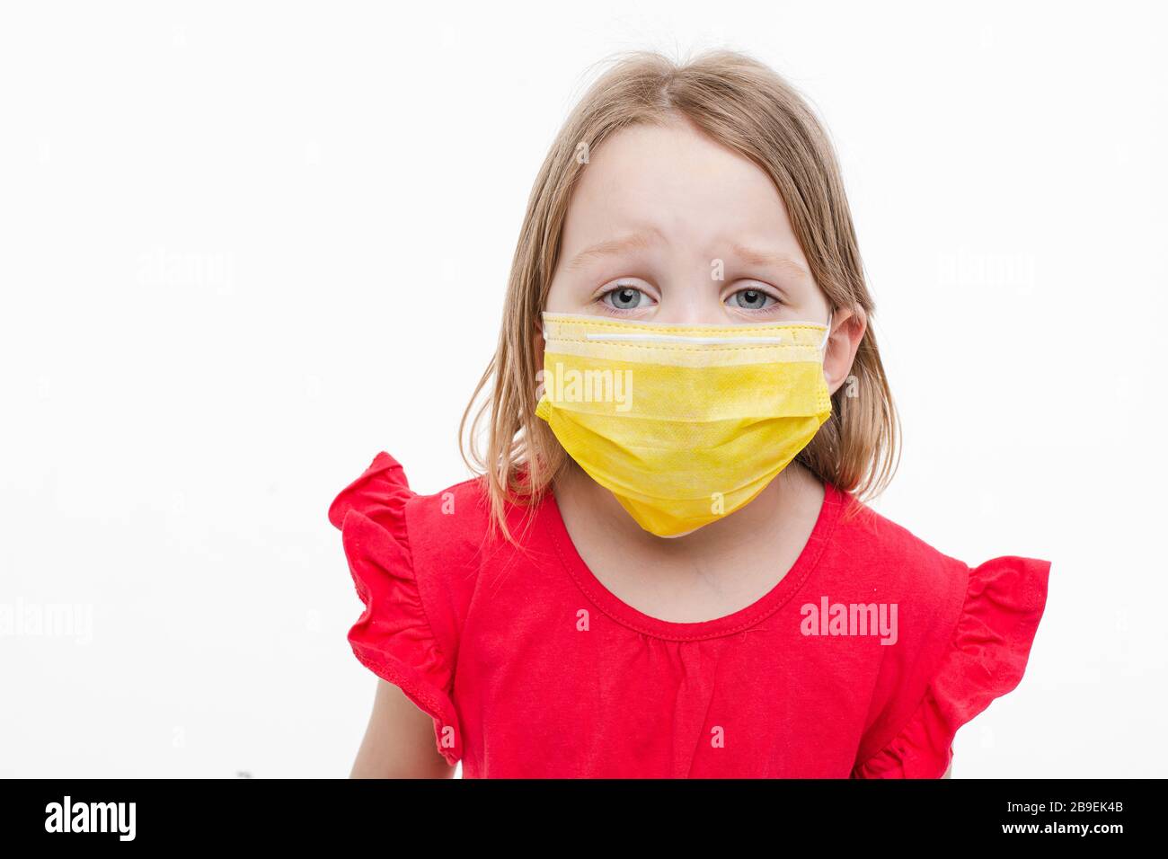 Portrait of little girl with yellow medical mask on her face is scared ...