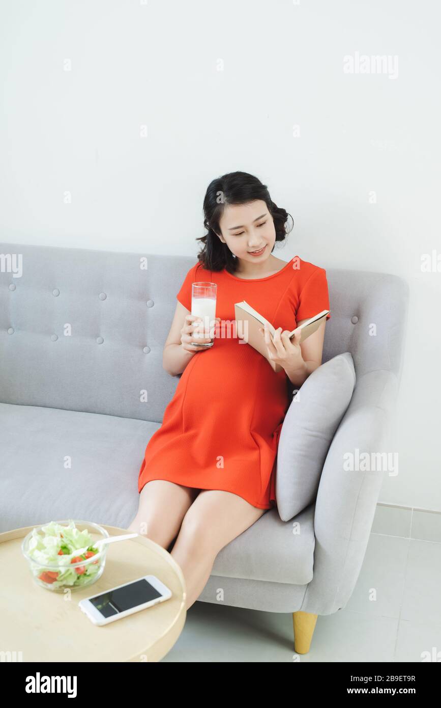 Young Asian woman reading book relaxing at sofa and drinking milk Stock ...