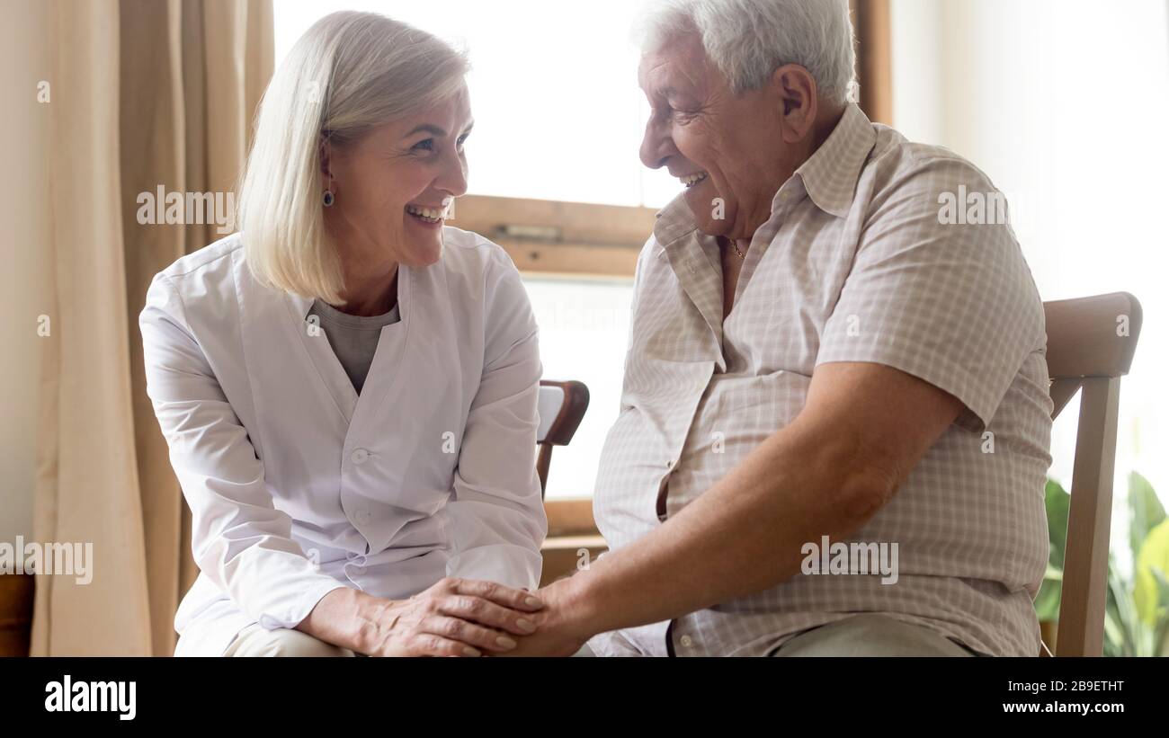 Friendly smiling mature doctor holding happy older patient hands Stock ...