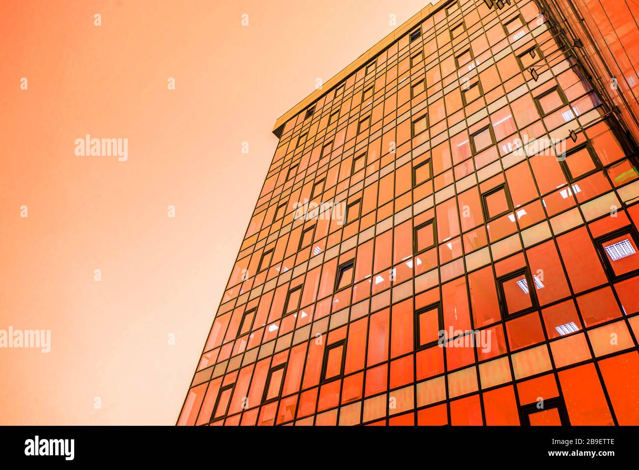 orange building made of glass against the sky, red tinted. lines and ...
