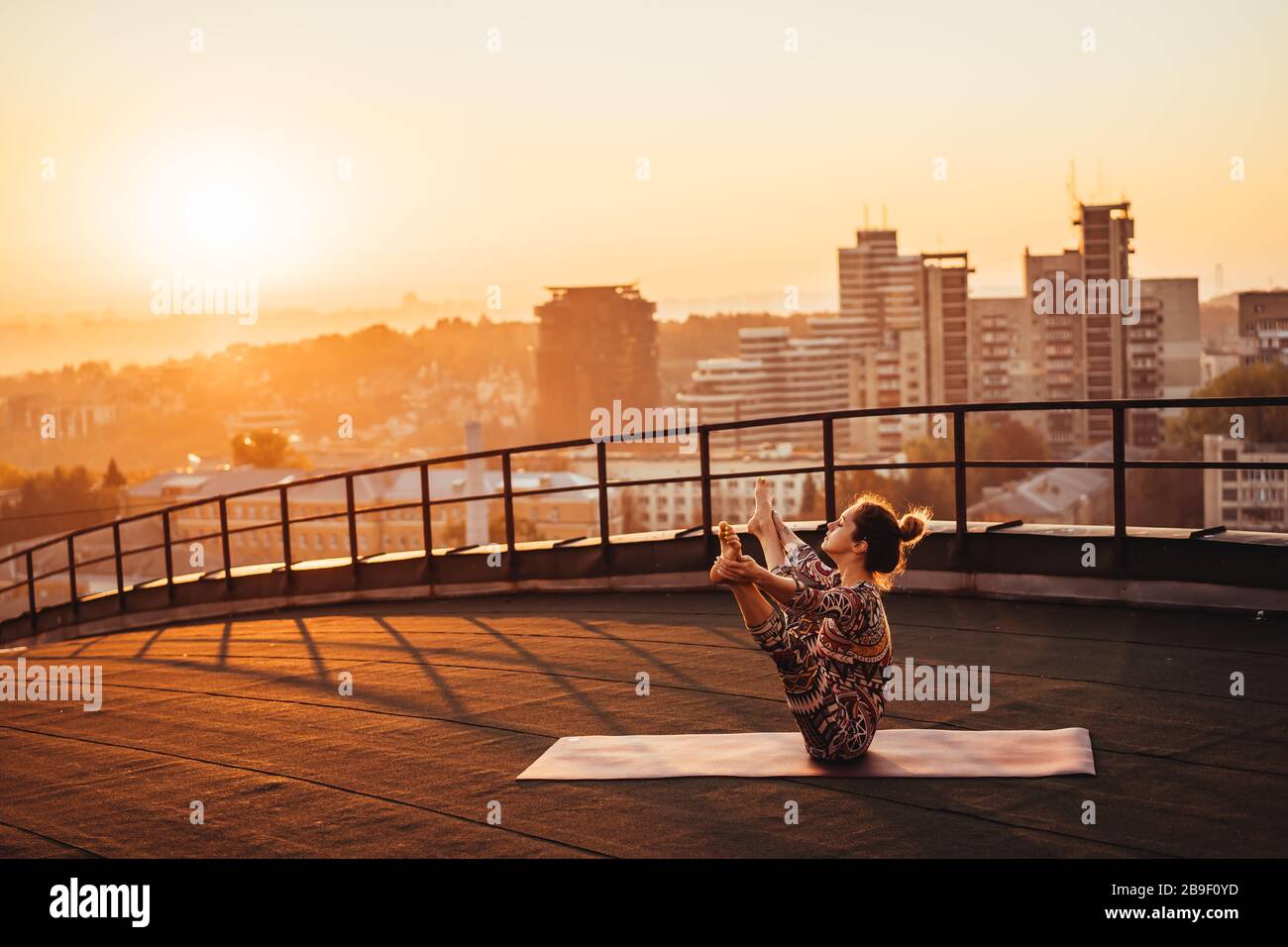 Woman doing yoga on the roof of a skyscraper in big city Stock Photo ...
