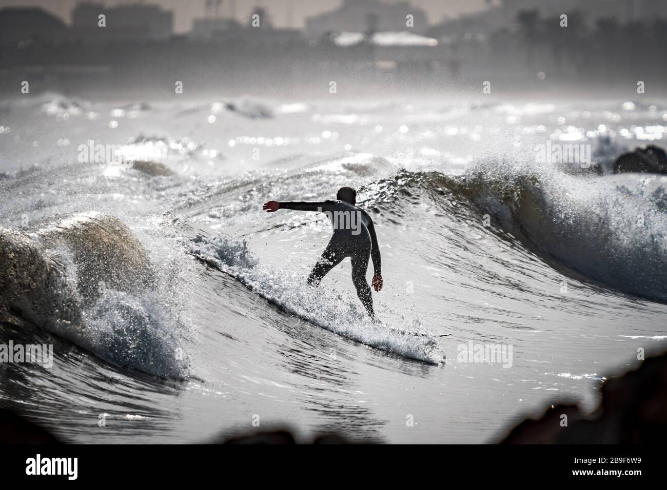 High contrast of unrecognizable surfer surfing near the city Stock ...