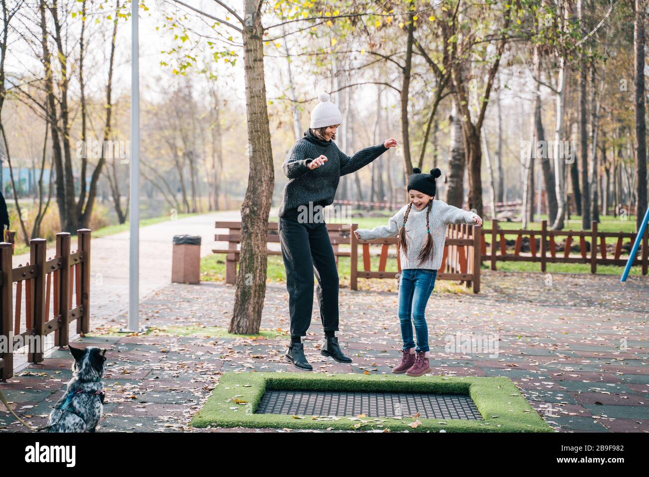 Mom And Her Daughter Jumping Together On Trampoline In Autumn Park