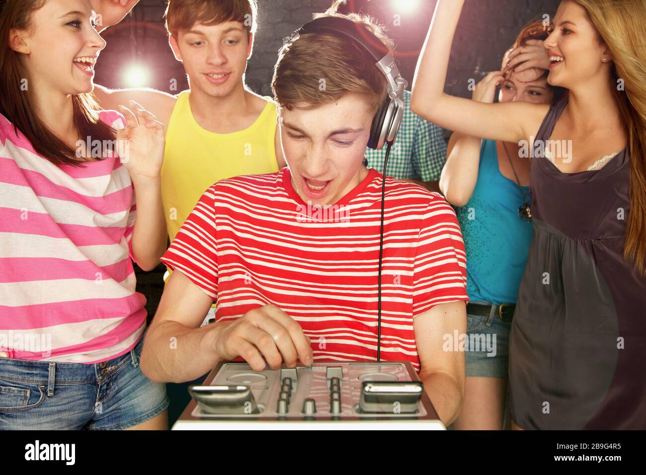 Teenage boy DJ playing music for friends dancing at party Stock Photo ...