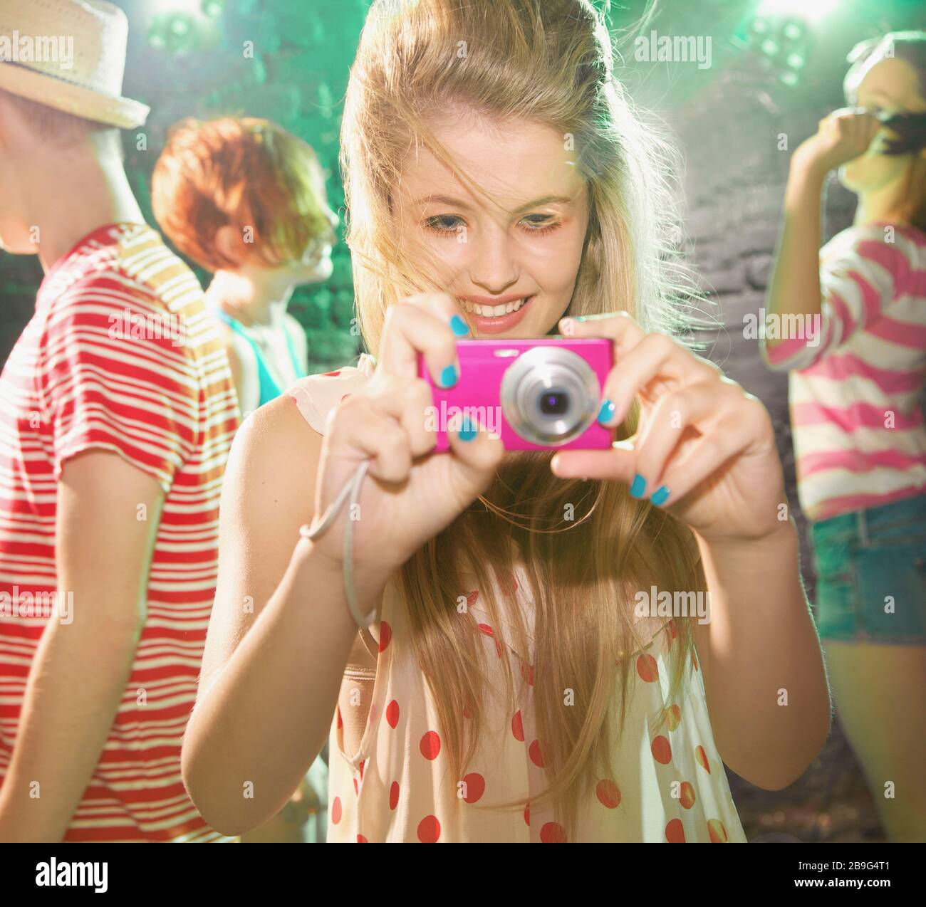 Playful teenage girl using digital camera at party Stock Photo - Alamy