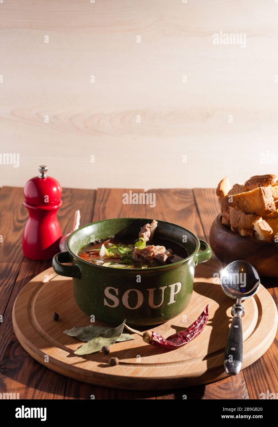 Rustic meat bone soup / broth sprinkled with green onions on a wooden ...