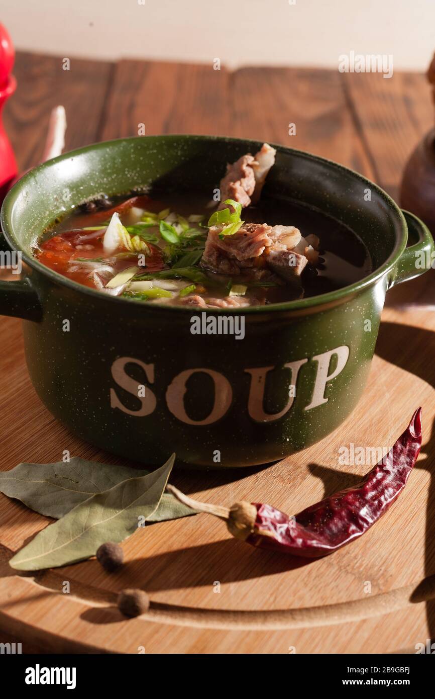 Rustic meat bone soup / broth sprinkled with green onions on a wooden ...