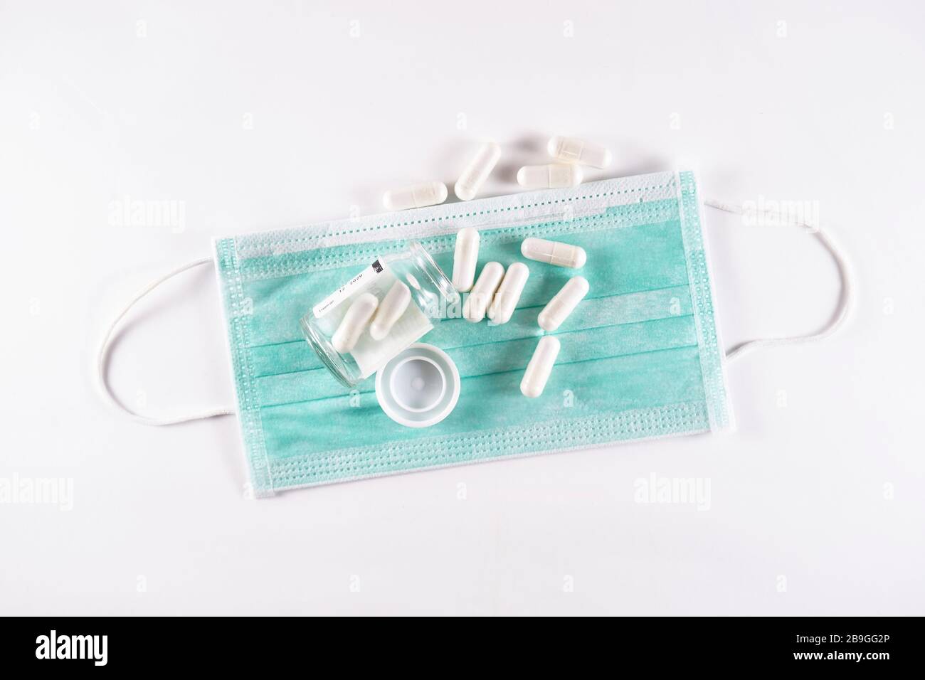 White medicine capsules spilling out of glass bottle on top of a ...