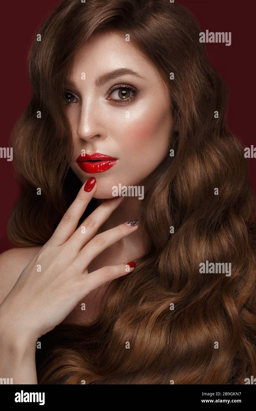 Beautiful girl with a classic make up, curls hair and red nails ...