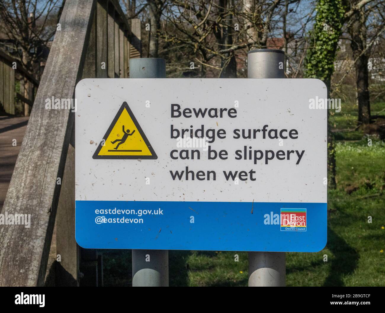 Sign on a wooden footbridge - bridge surface may be slippery when wet ...